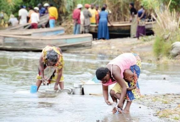 Photo: Woman washing utensils and a child defecating in the same lake