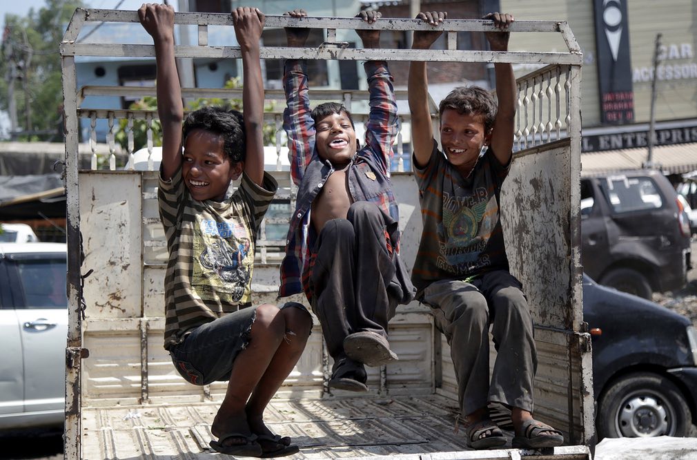 Young rag pickers play outside their shop in a transport yard in India