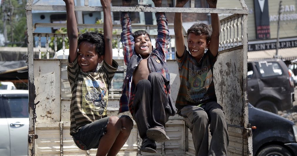 Young rag pickers play outside their shop in a transport yard in India