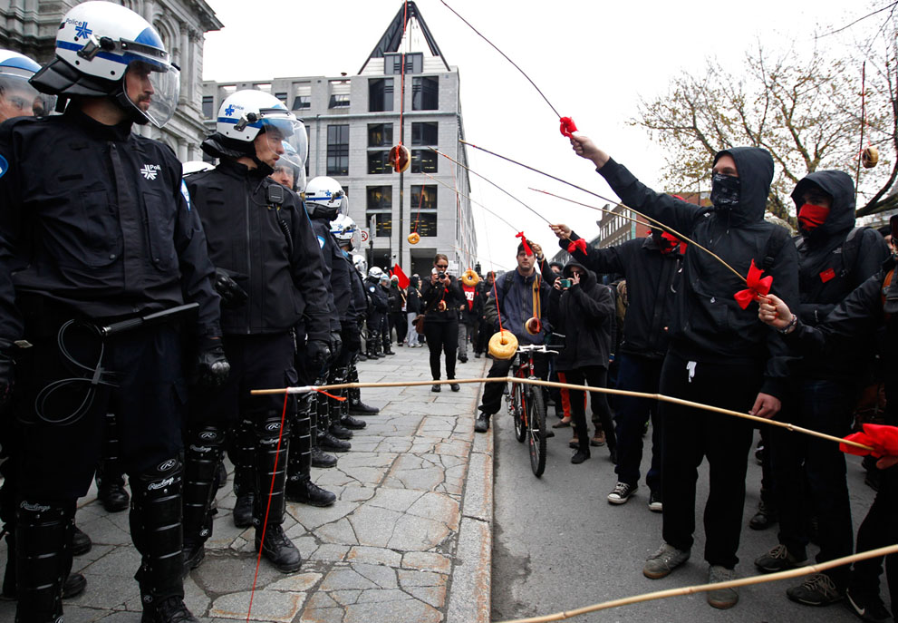 Montreal protesters holding donuts with sticks in front of Police in ...