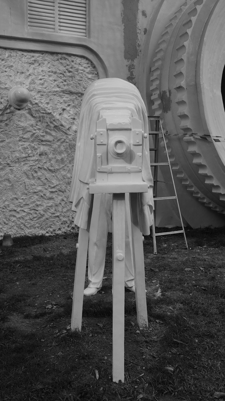 Sculpture of an old camera operated by a statue of a person at the back ...