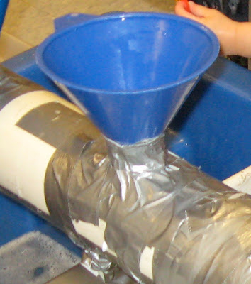 SAND AND WATER TABLES: LARGE PLASTIC TUBE WITH FUNNELS